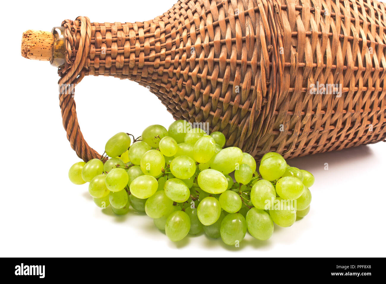 White grape with old wicker wrapped glass bottle on white background ...