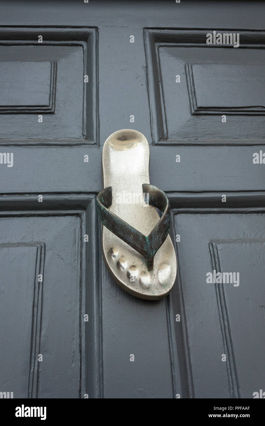 Door knocker in the shape of a flip flop (or thong) on a dark grey wood ...