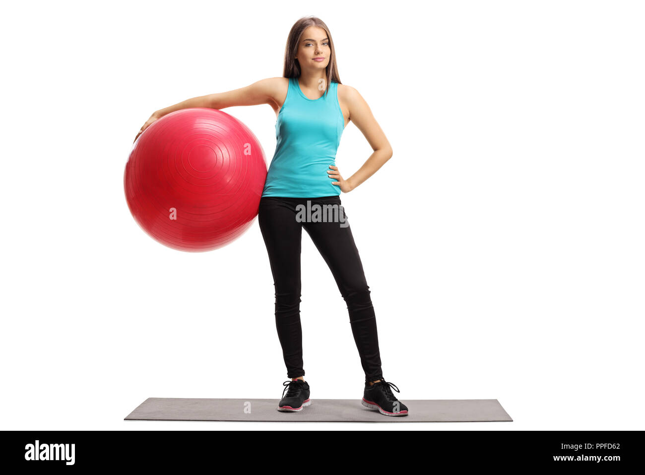 Full length portrait of a young female with a pilates ball standing on ...