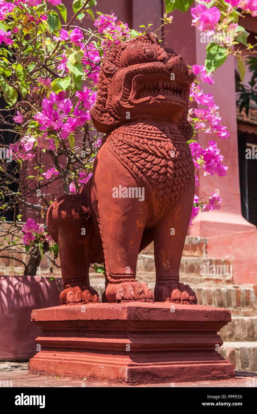 Red stone statue of a mythical guardian lion figure in the grounds of ...