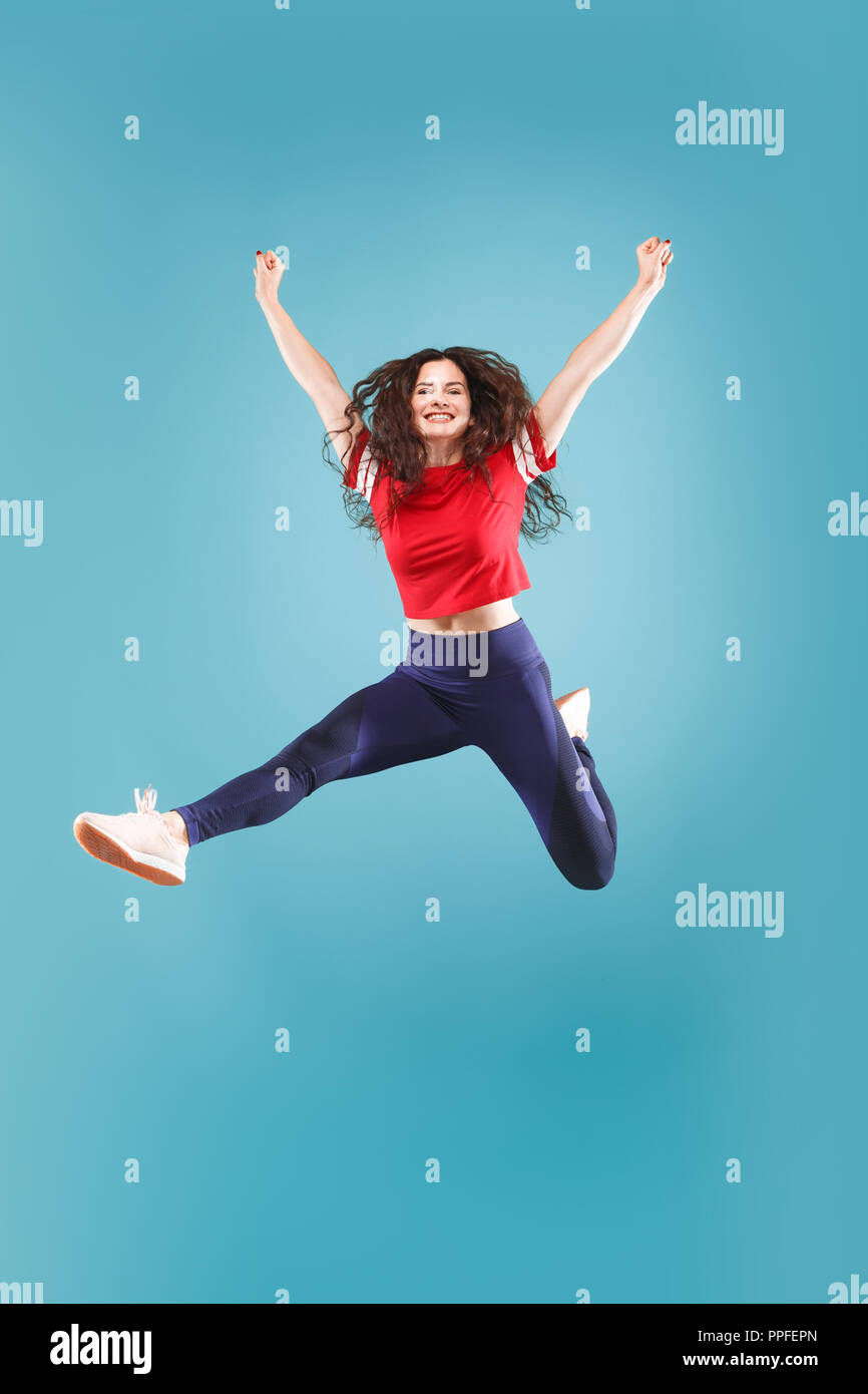 I am happy. Mid-air shot of pretty smiling young woman jumping and ...