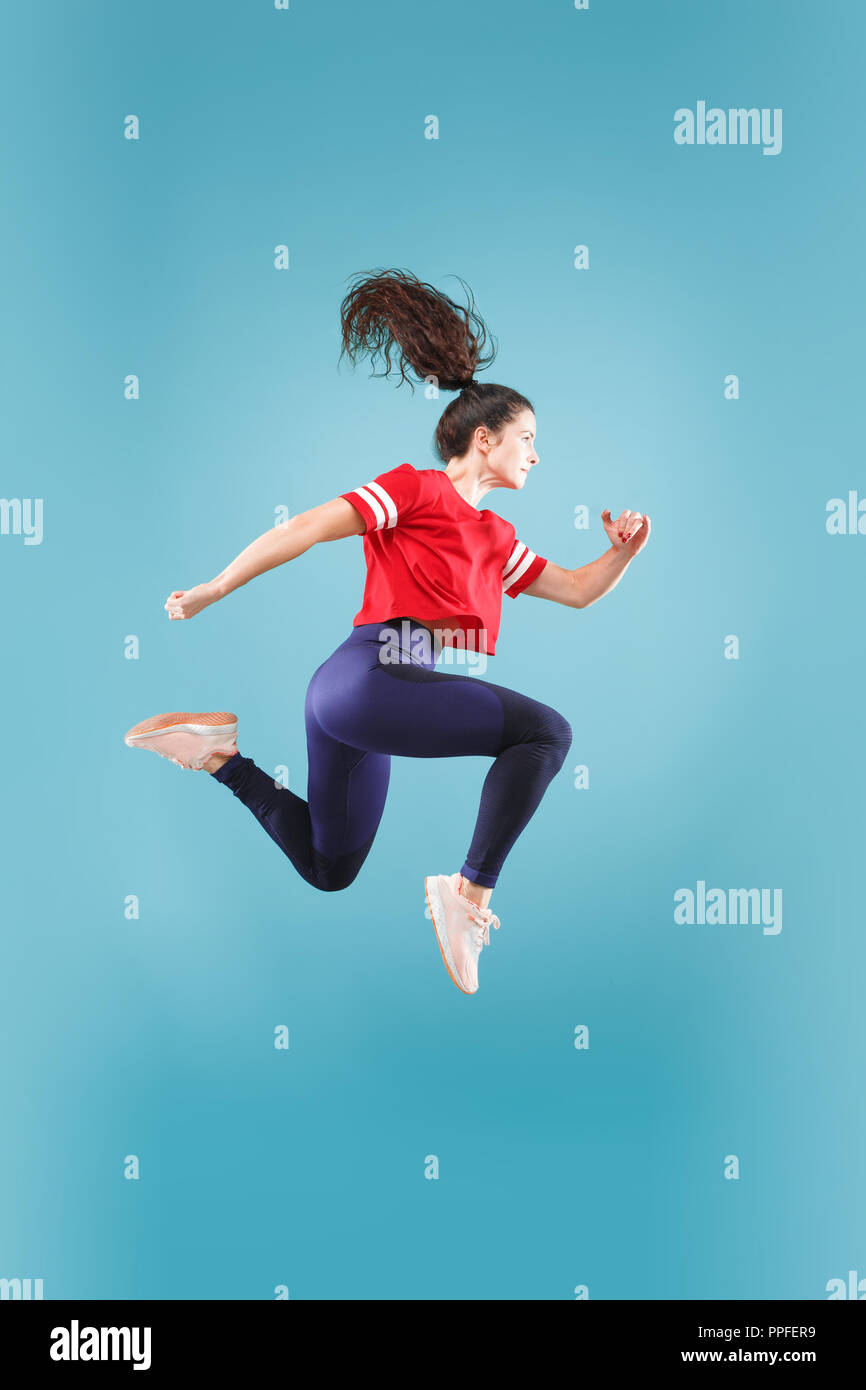 I am happy. Mid-air shot of pretty smiling young woman jumping and ...