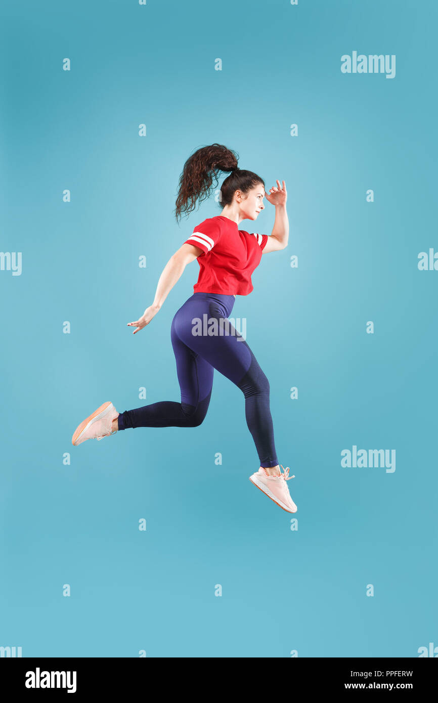 I am happy. Mid-air shot of pretty smiling young woman jumping and ...