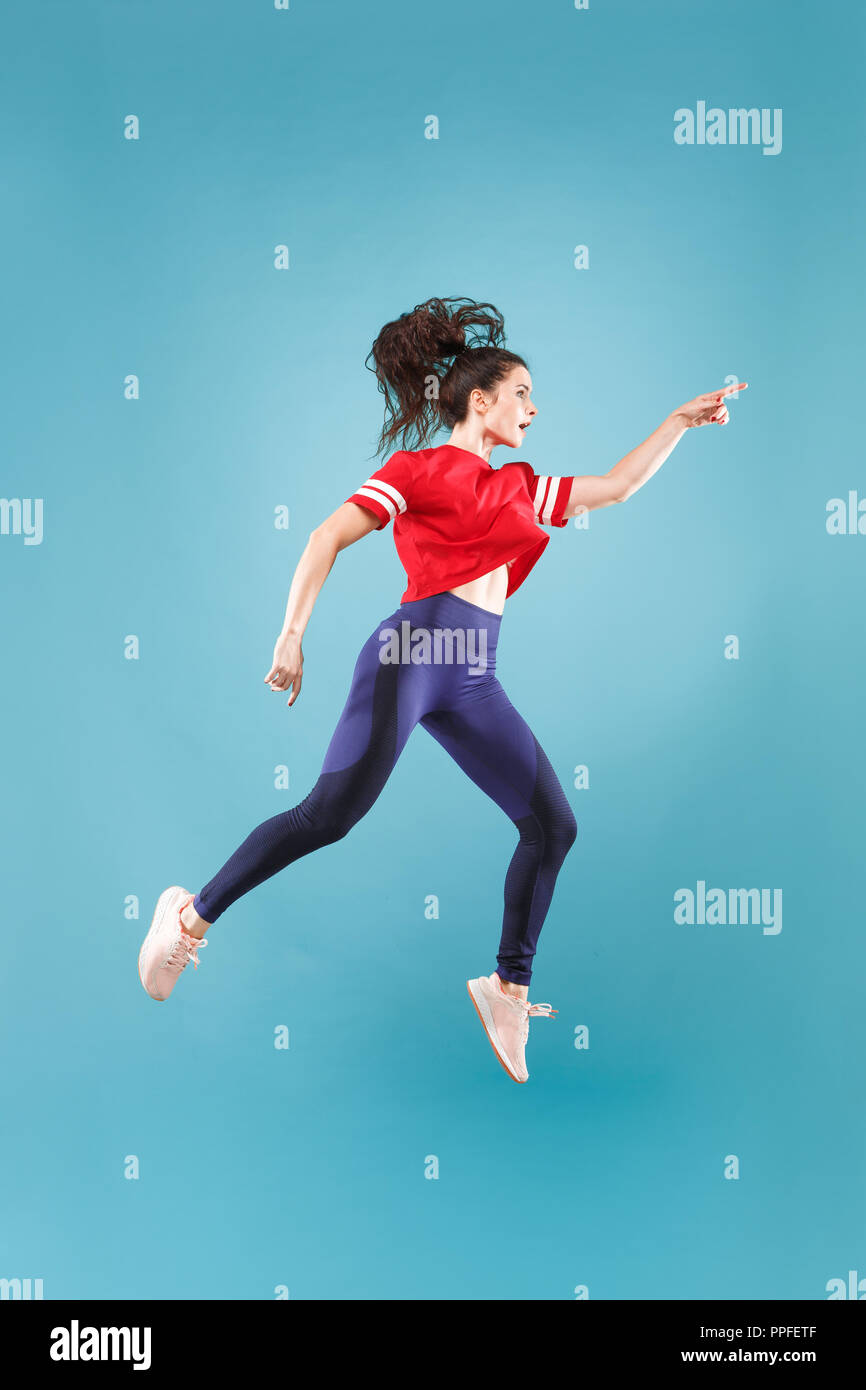 I am happy. Mid-air shot of pretty smiling young woman jumping and ...