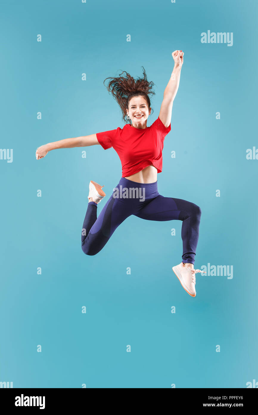 I am happy. Mid-air shot of pretty smiling young woman jumping and ...