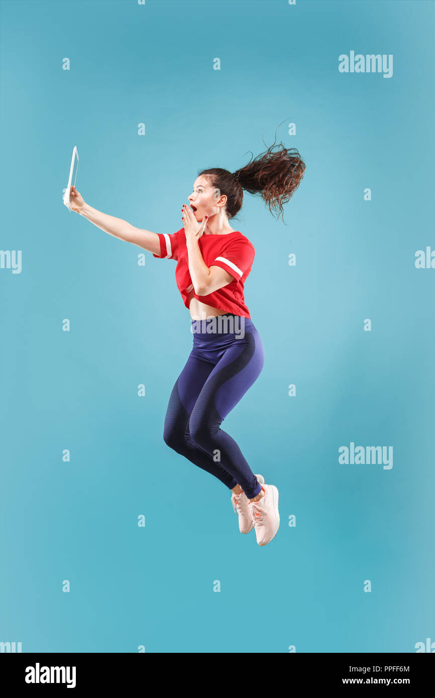 Gadget in modern life. Jump of young woman over pink studio background ...