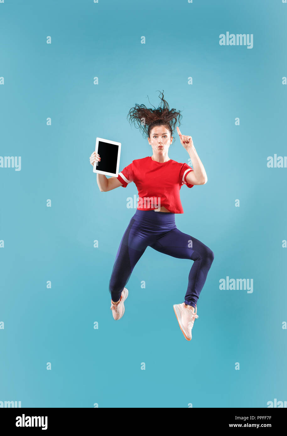 Gadget in modern life. Jump of young woman over pink studio background ...