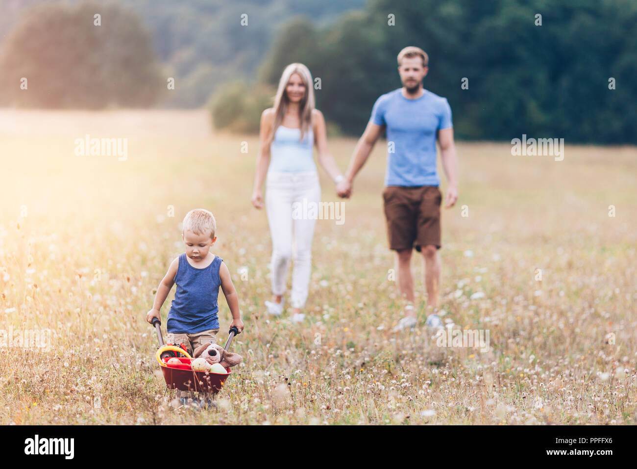 Adorable child with his parents pushing a whellbarrow outdoors Stock ...