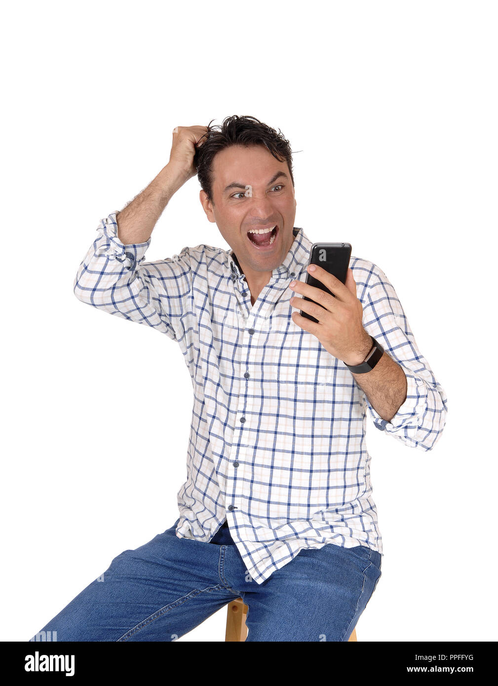 A young man holding up his phone, looking very surprised what is on his ...