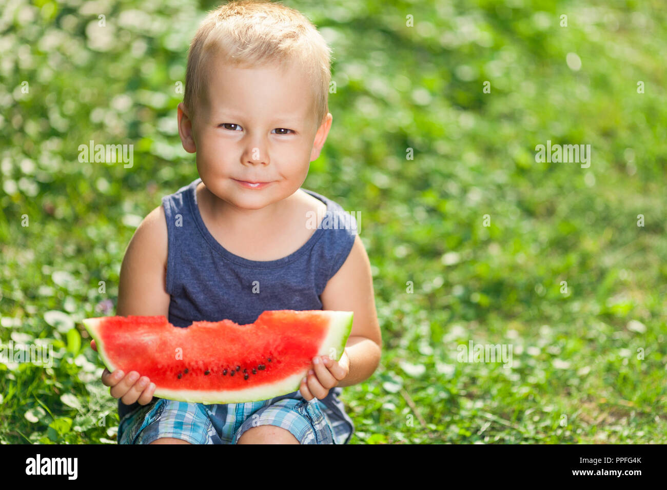 Cute toddler sitting outdoords and eating a slice of watermelon Stock ...