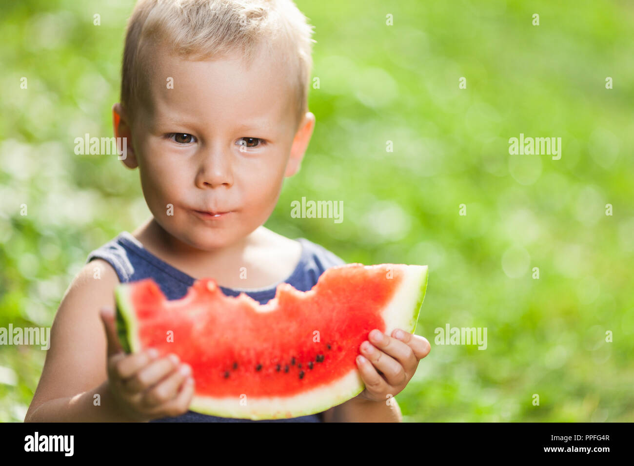 Cute toddler sitting outdoords and eating a slice of watermelon Stock ...