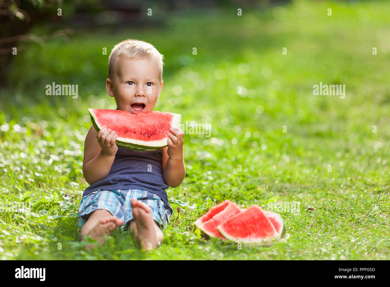 Cute toddler sitting outdoords and eating a slice of watermelon Stock ...