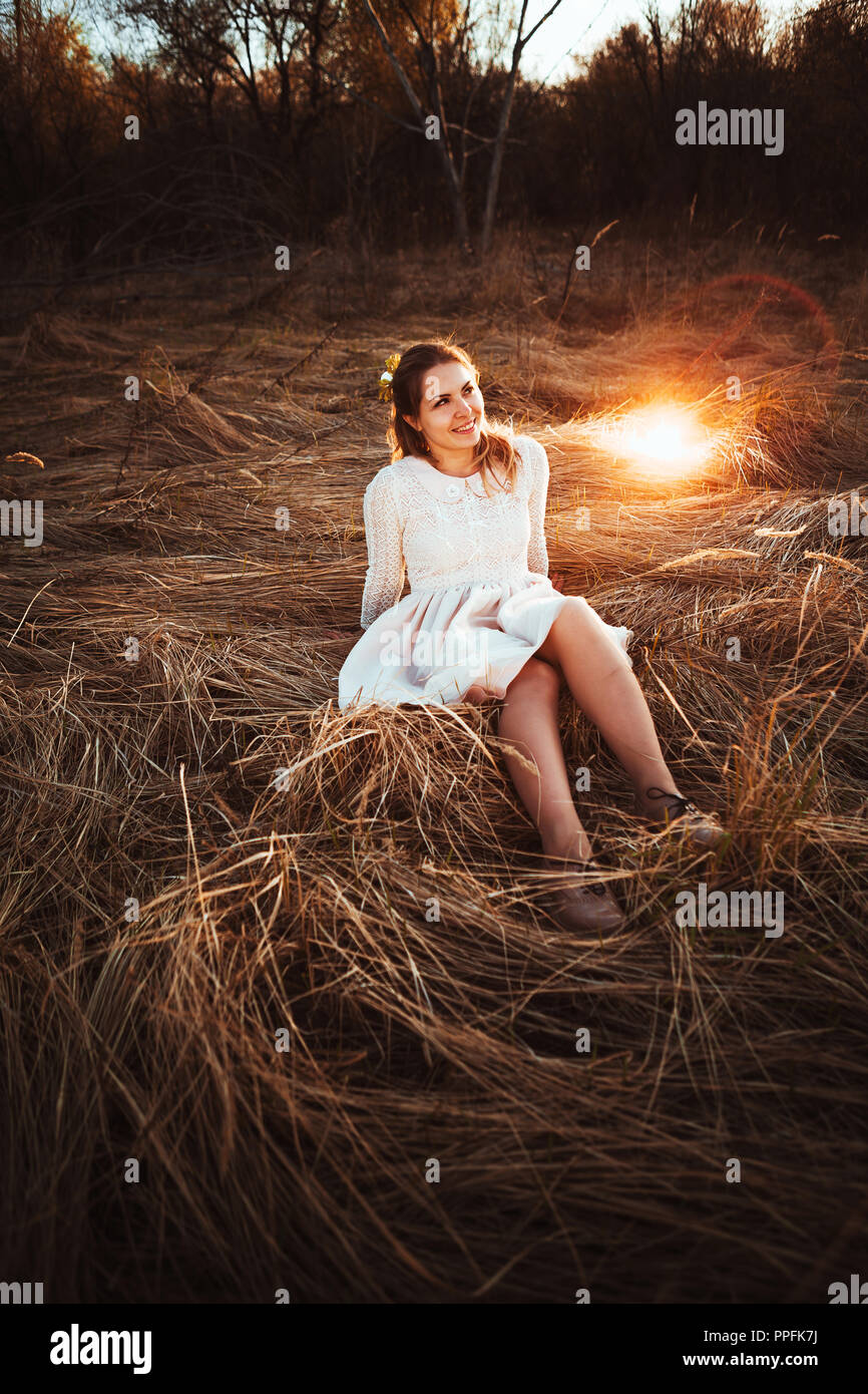girl is sitting in the field on the sunset background Stock Photo - Alamy