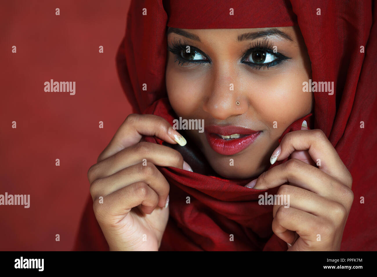 Young pretty woman with oriental look holds with hands a red scarf ...