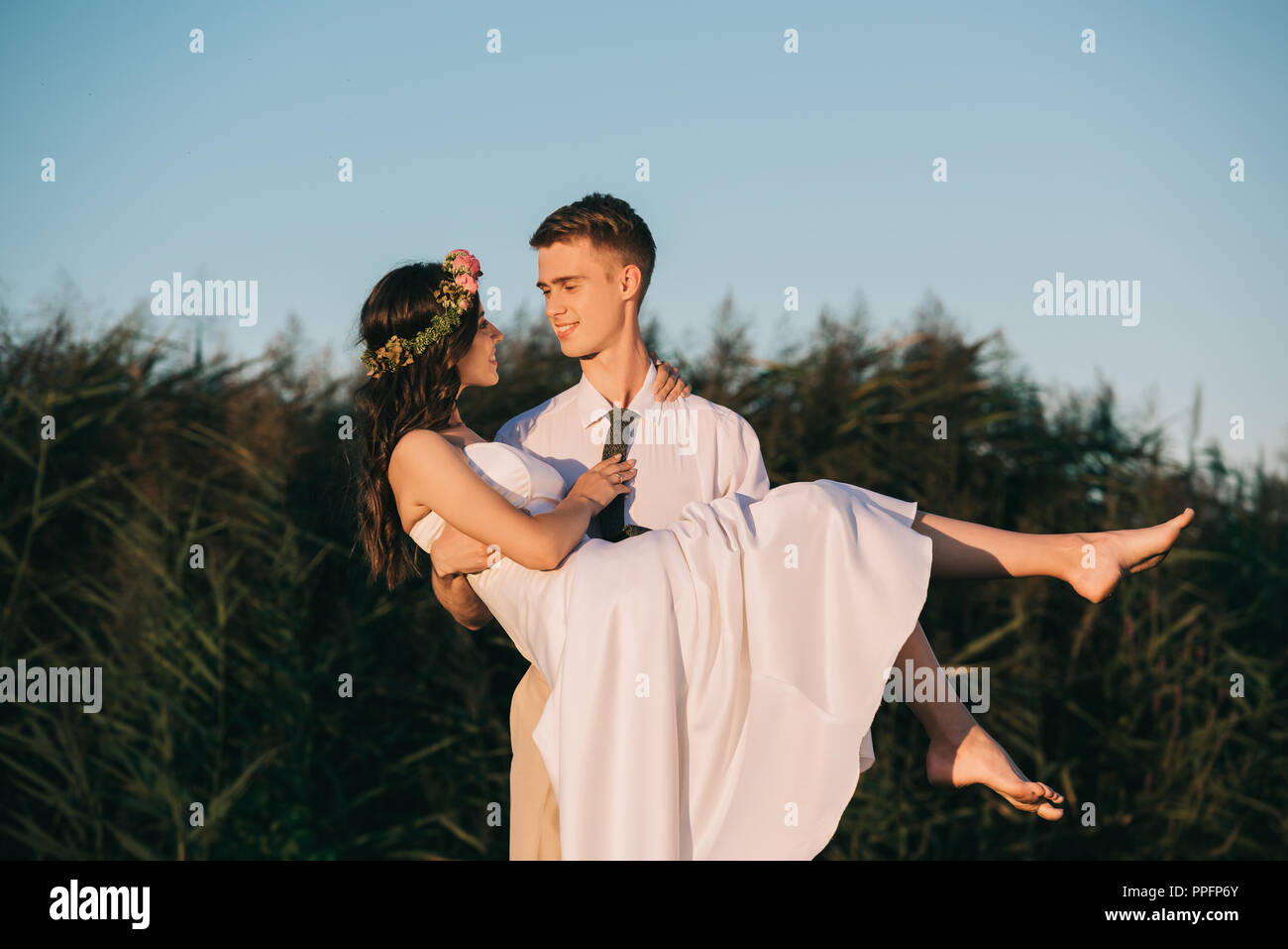 Handsome groom carrying bride hi-res stock photography and images - Alamy