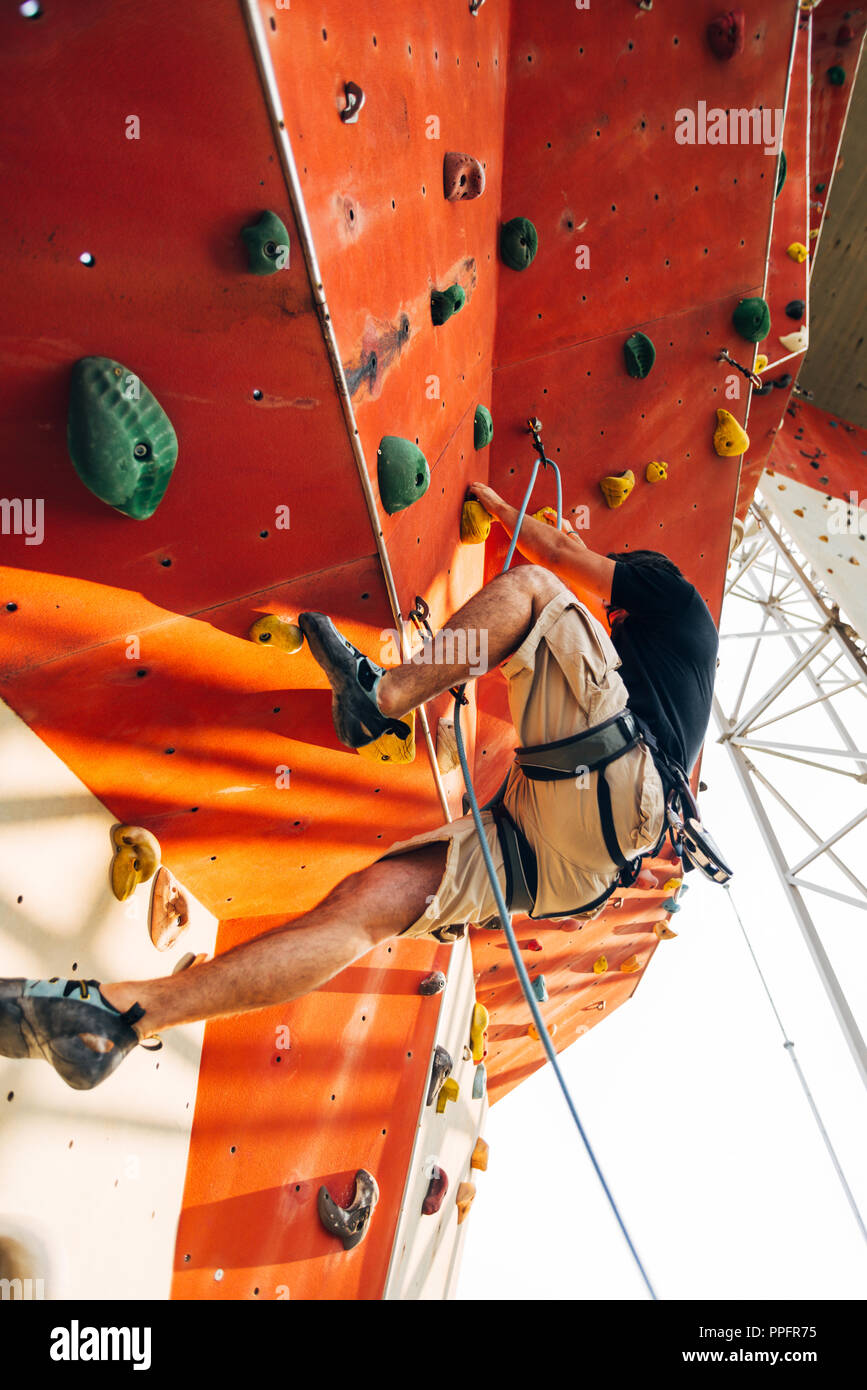 Young climber guy climbing on practical rock in climbing center ...