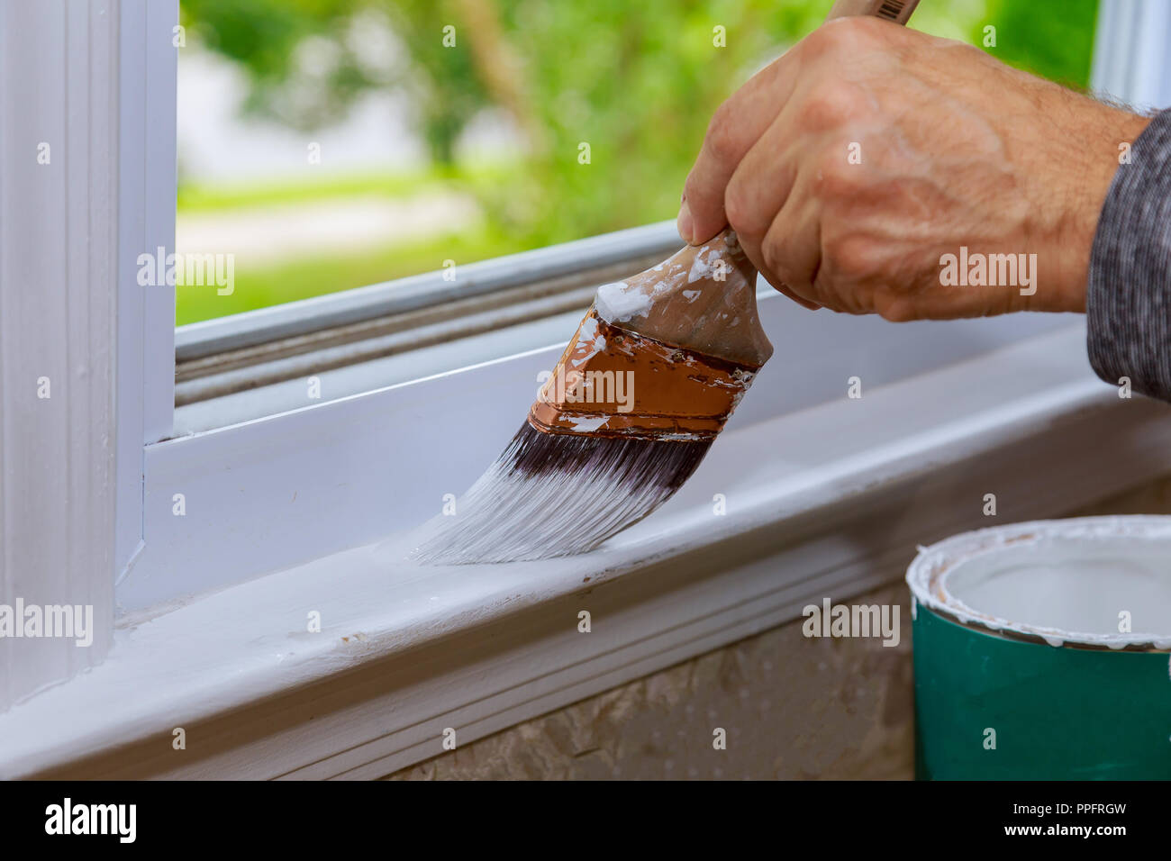 Painting a wooden window paint with paintbrush while painting window ...