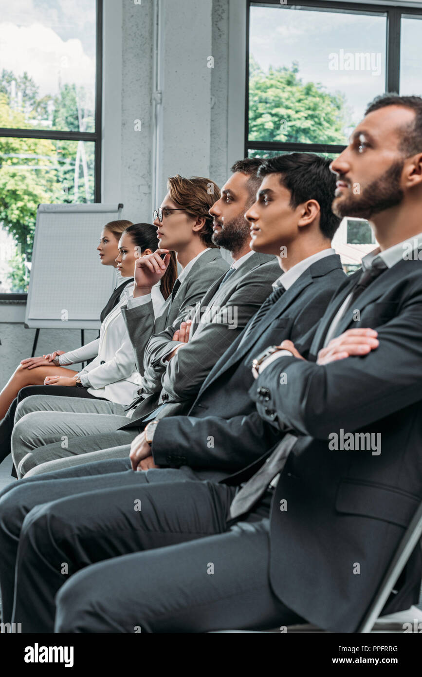 side view of businesspeople sitting on chairs during training in hub ...