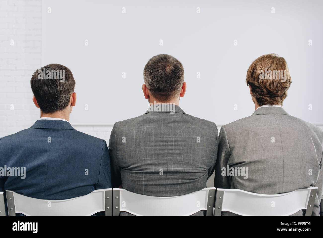 back view of three businessmen sitting on chairs during training in hub ...