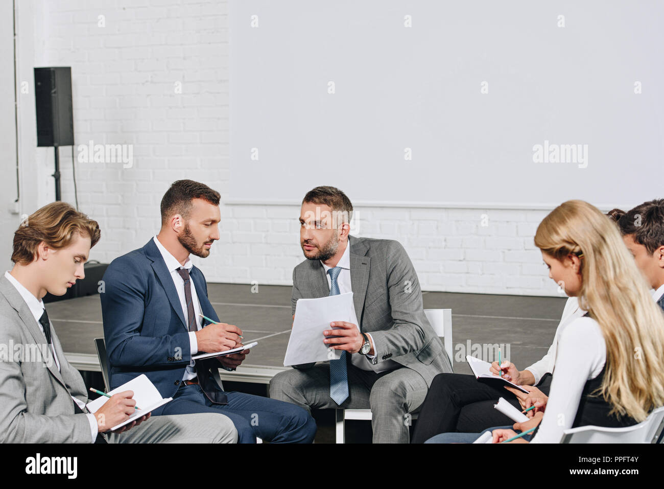 businesspeople sitting on chairs during training in hub Stock Photo - Alamy