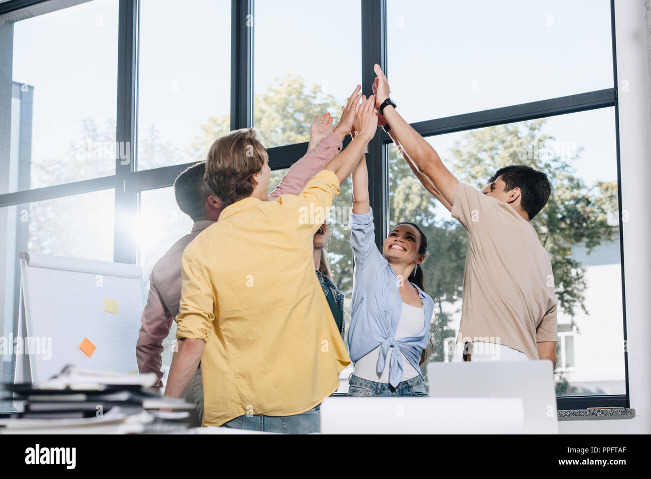 happy businesspeople celebrating success and giving high five in office ...