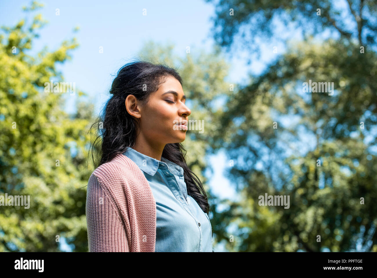 side view of attractive african american woman standing with closed ...
