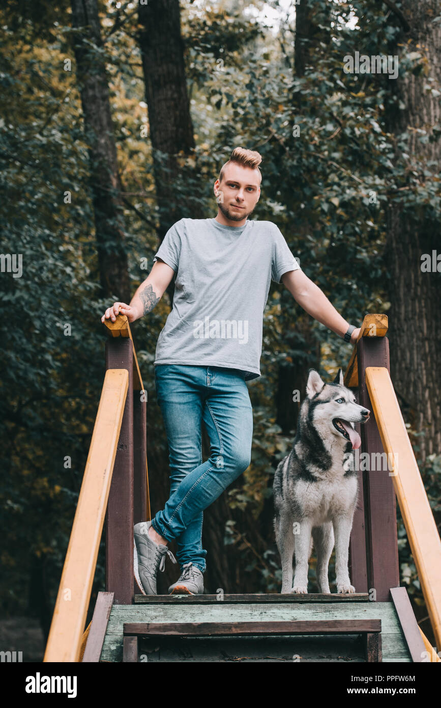 young man posing on stairs with husky dog Stock Photo - Alamy