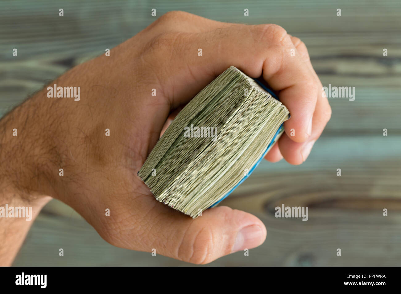 Man holding a fistful of banknotes tied with a rubber band with the ...