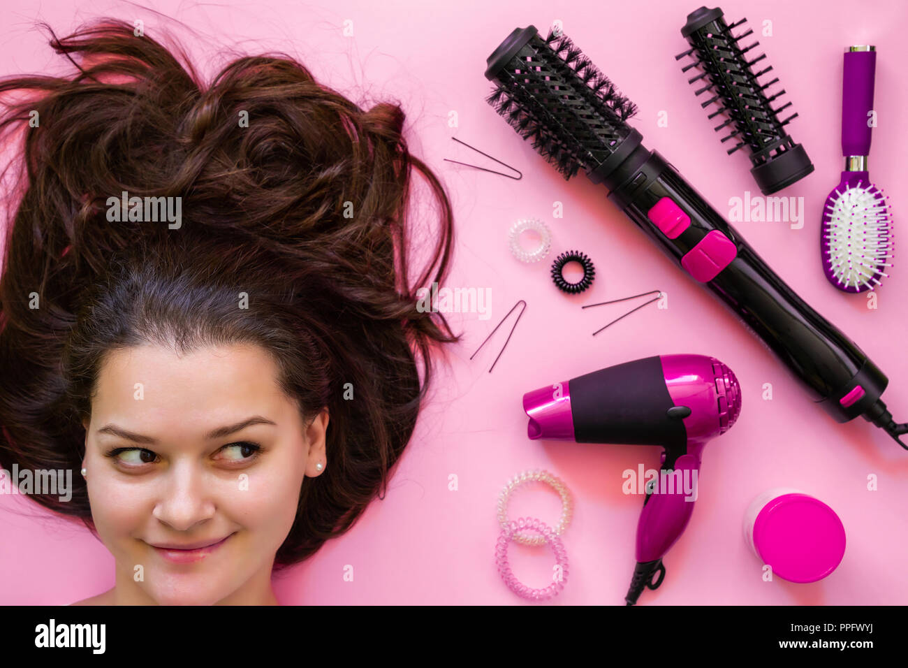 Portrait of brunette and professional hairdressing tools on pink ...