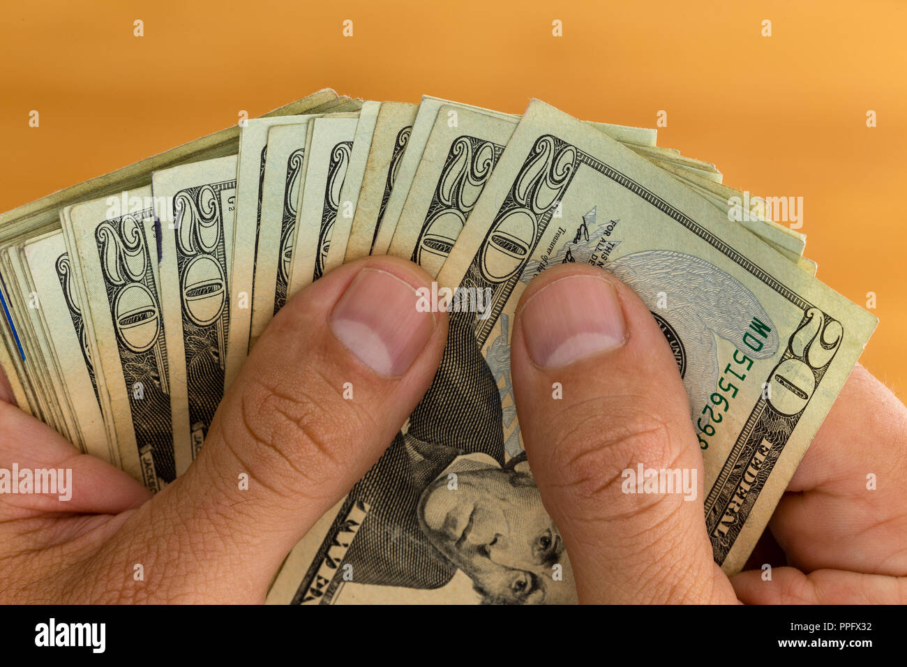 Man checking or counting a handful of 20 USD banknotes in a close up ...