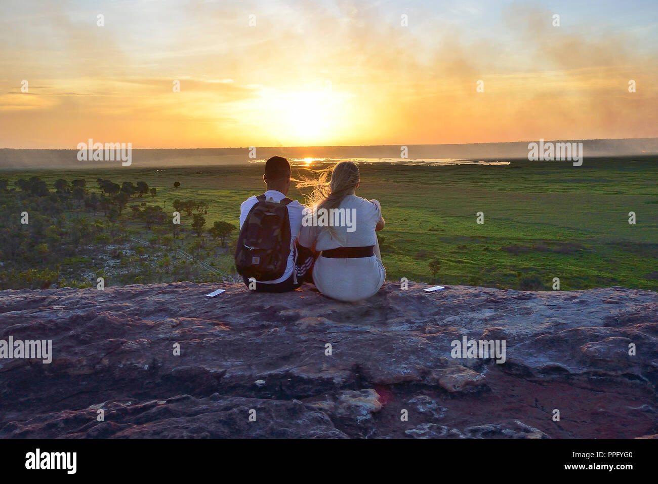 Two young people sit on the rocks at Ubirr Lookout to watch the sunset Kakadu National Park ...