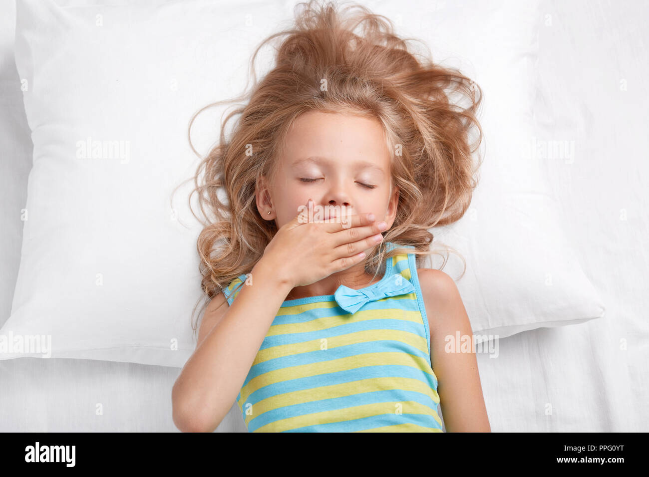 Pretty sleepy beautiful small female girl keeps eyes closed, palm on ...