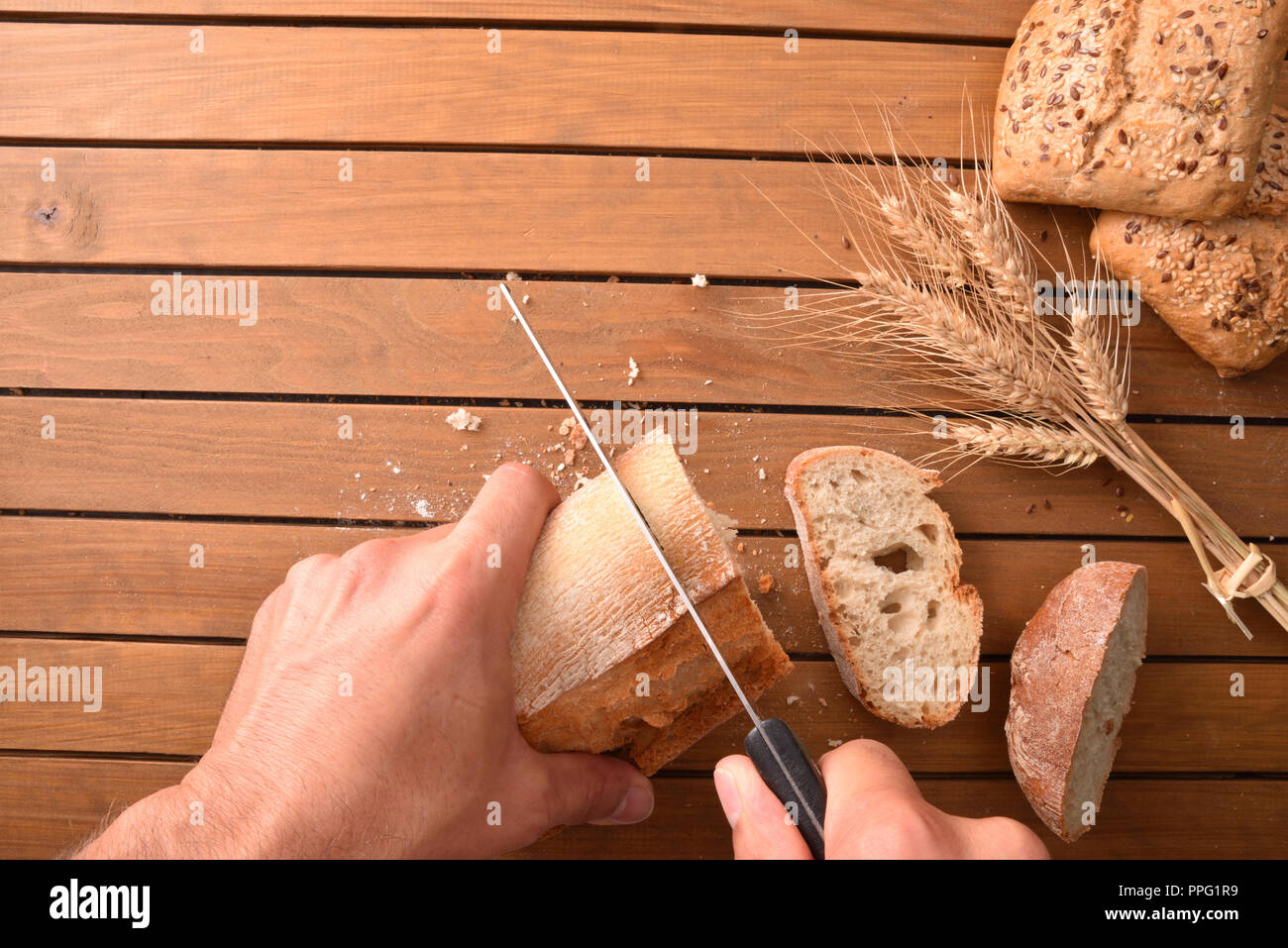 Hands cutting rustic loaf hi-res stock photography and images - Alamy