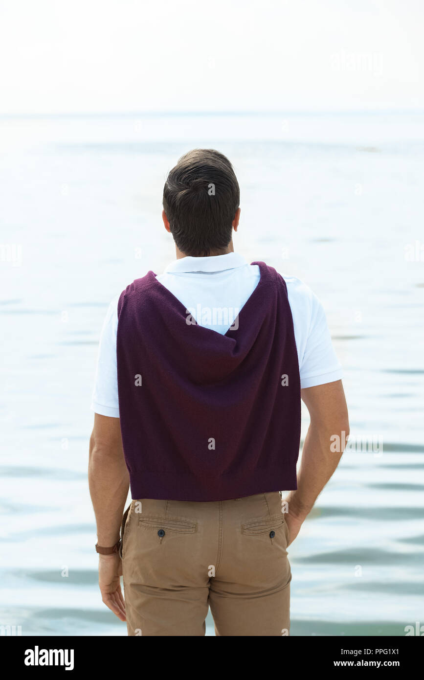 rear view of man standing and looking at river on summer day Stock ...