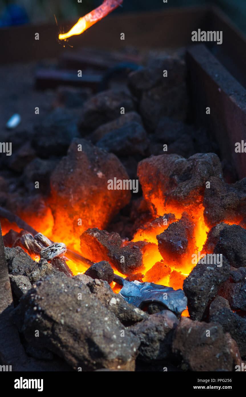 blacksmith furnace with burning coals, tools, and glowing hot metal ...