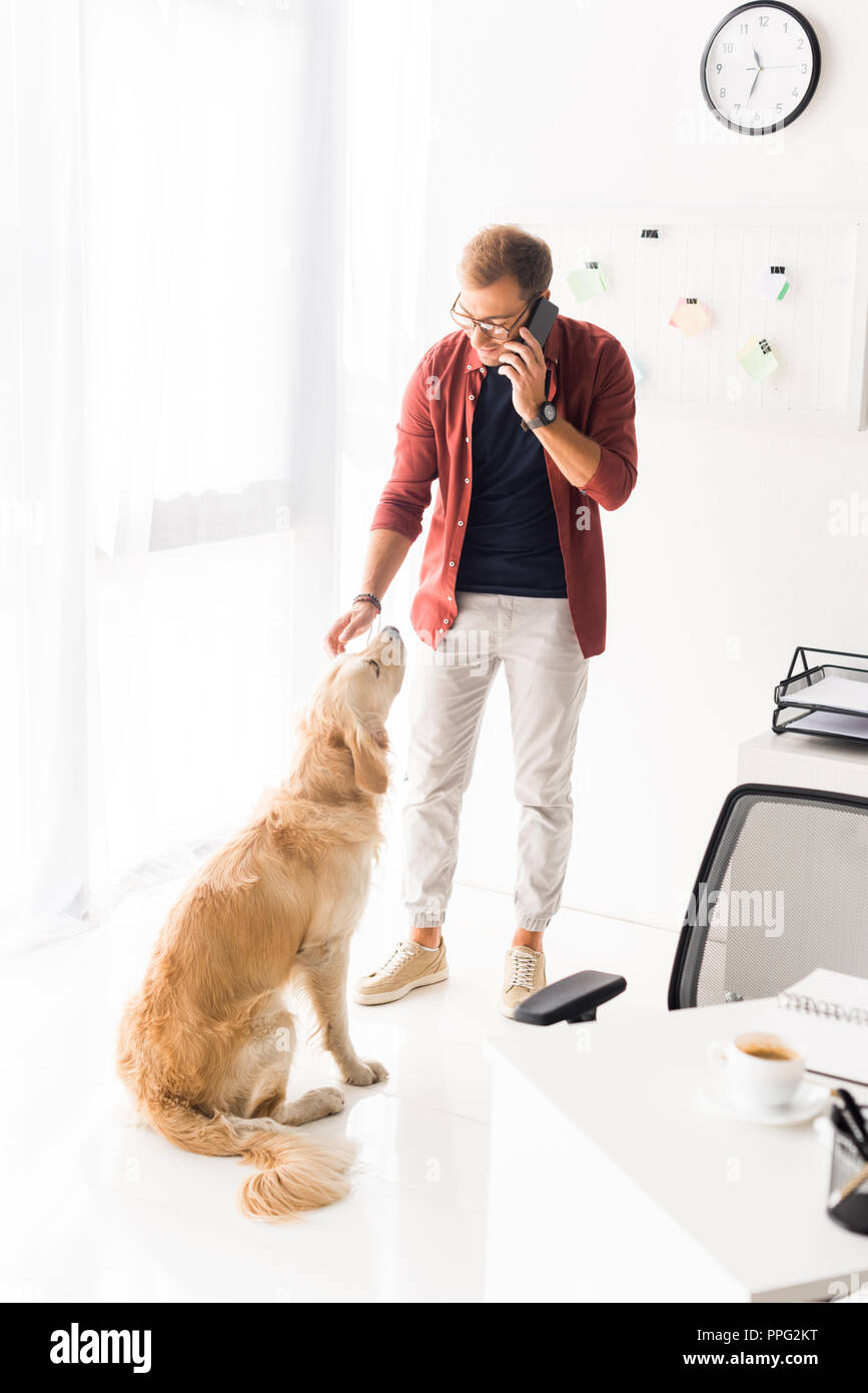 man talking on smartphone and stroking golden retriever dog Stock Photo ...
