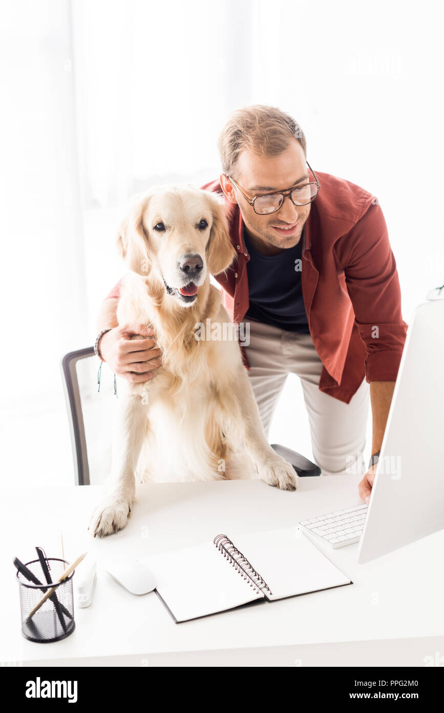 businessman hugging golden retriever while working in modern office ...