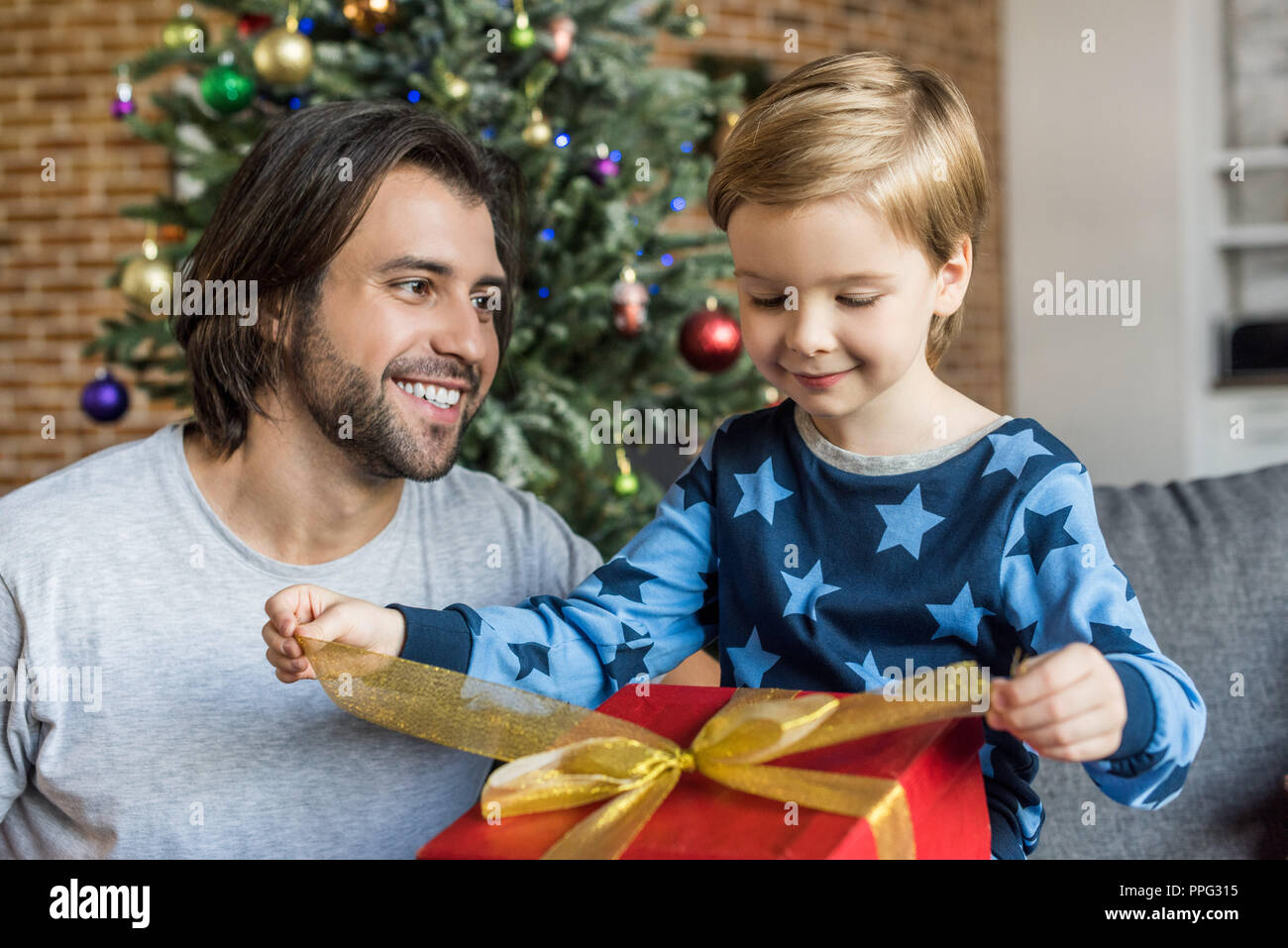 happy father looking at adorable little son opening christmas gift ...