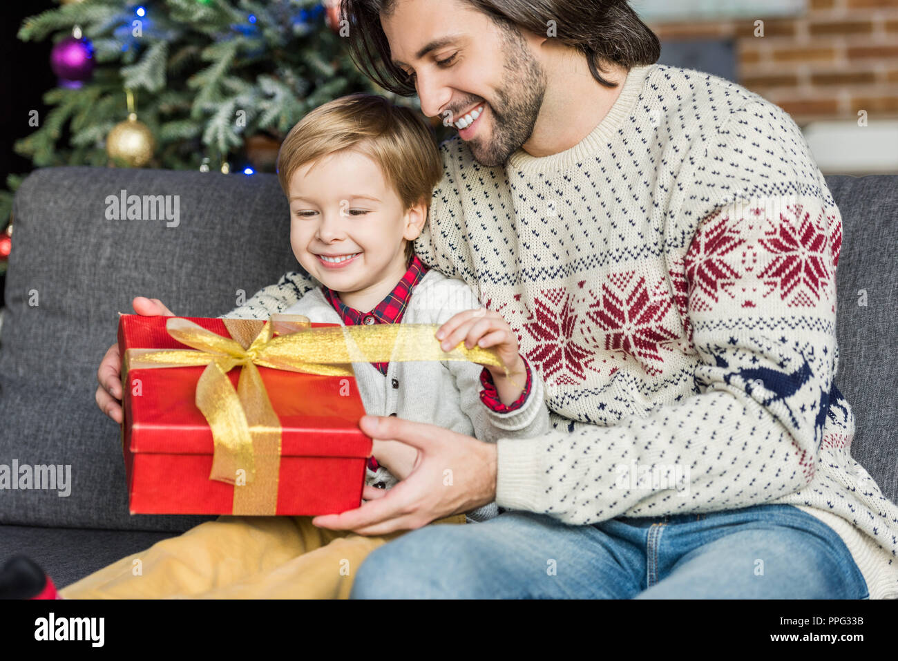 happy father looking at cute little son opening christmas present Stock ...