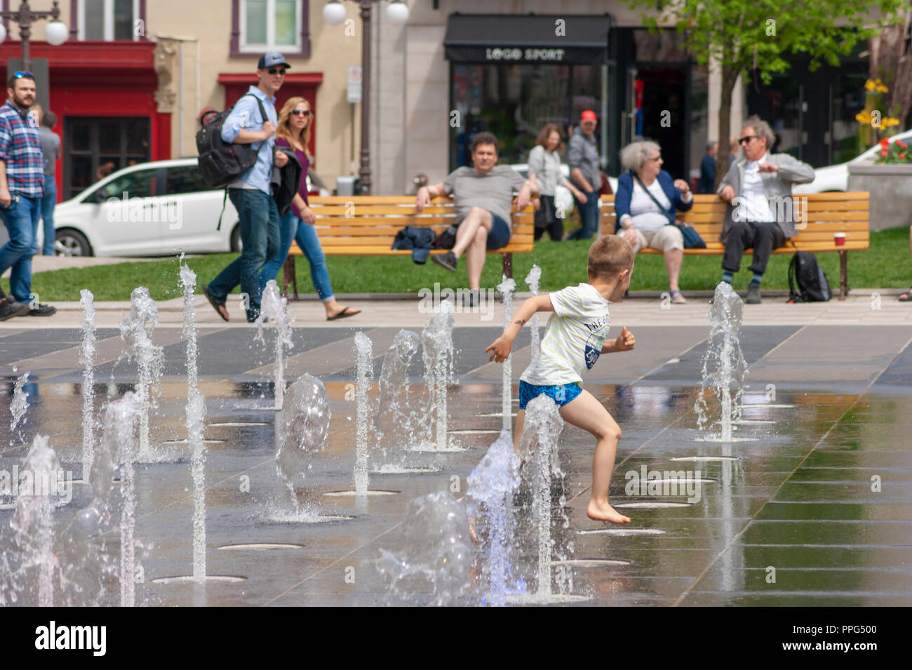 Boy having fun in a walk-in water games fountain, running between the ...
