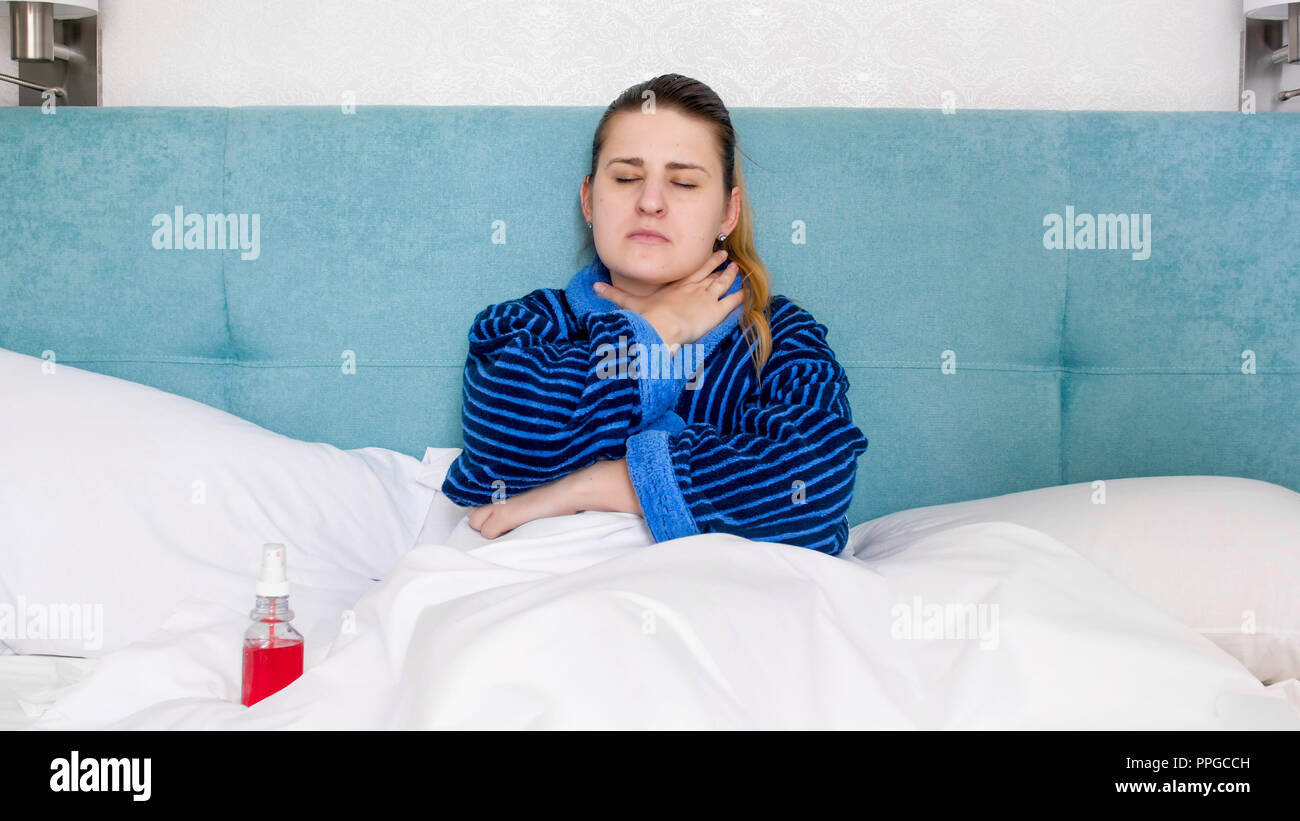 Portrait of sick woman with flu and sore throat holding hand on aching ...