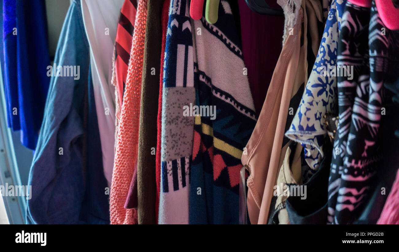 many colorful clothes hanging on pink hangers with different colors and ...