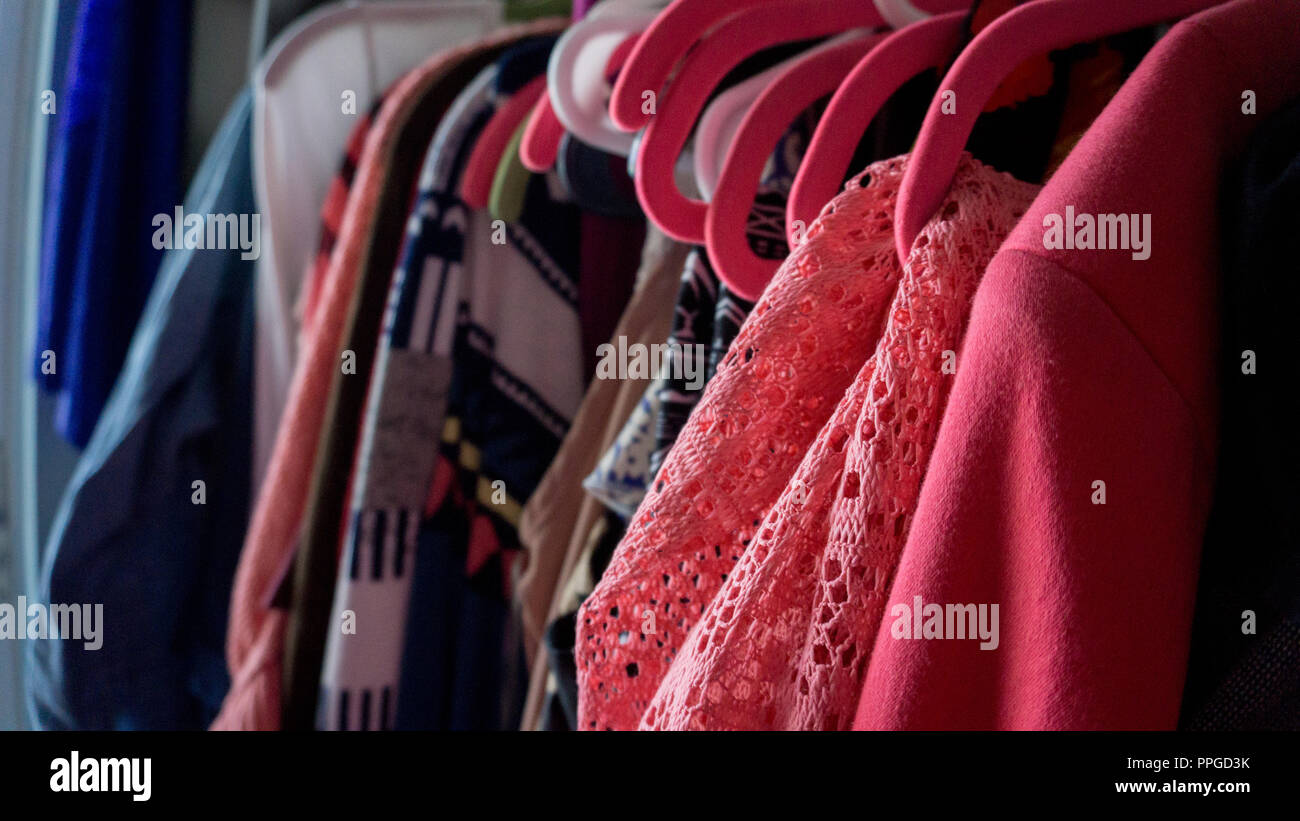 many colorful clothes hanging on pink hangers with different colors and ...