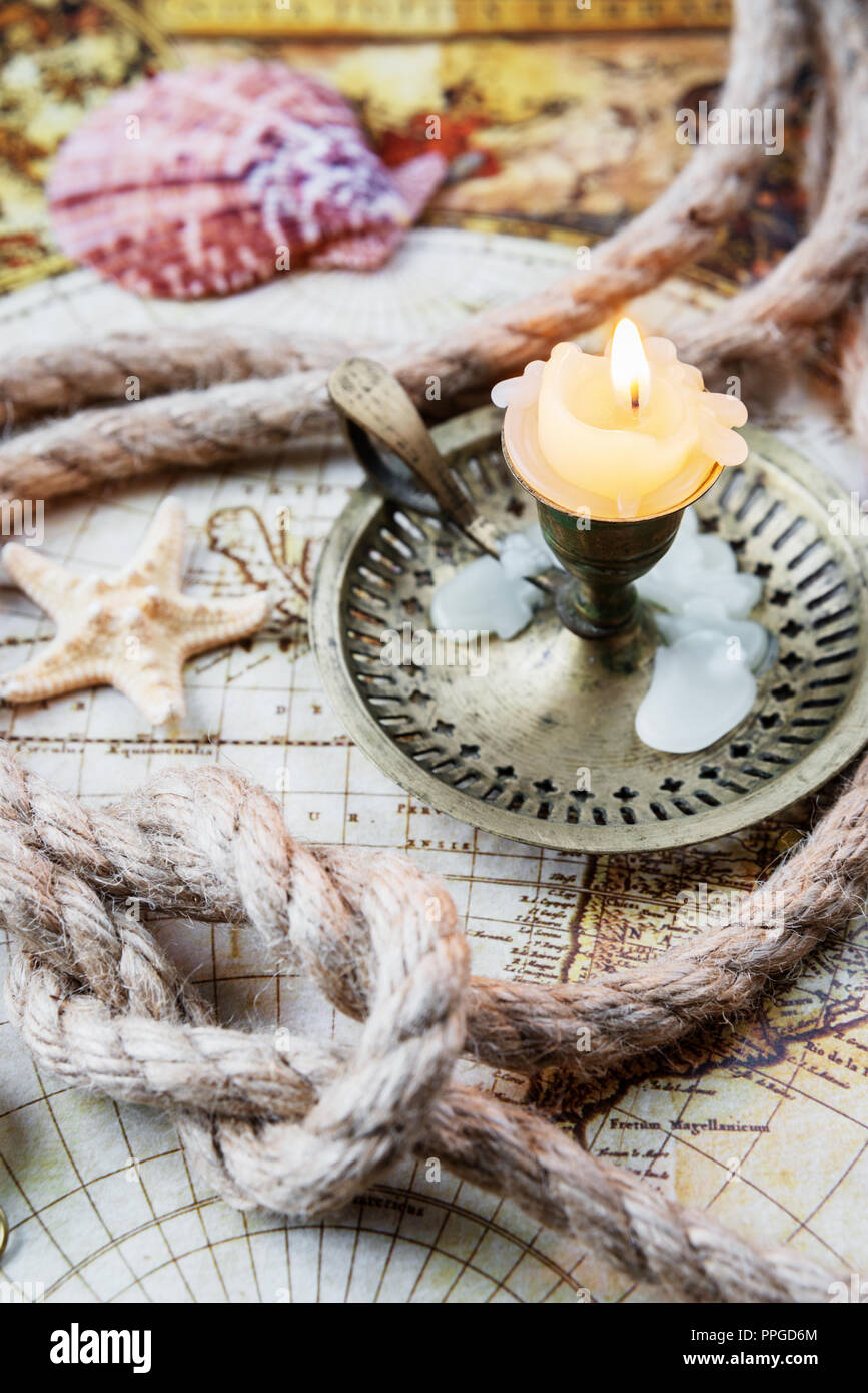 Time for adventures. Antique candlestick with a burning candle and rope ...