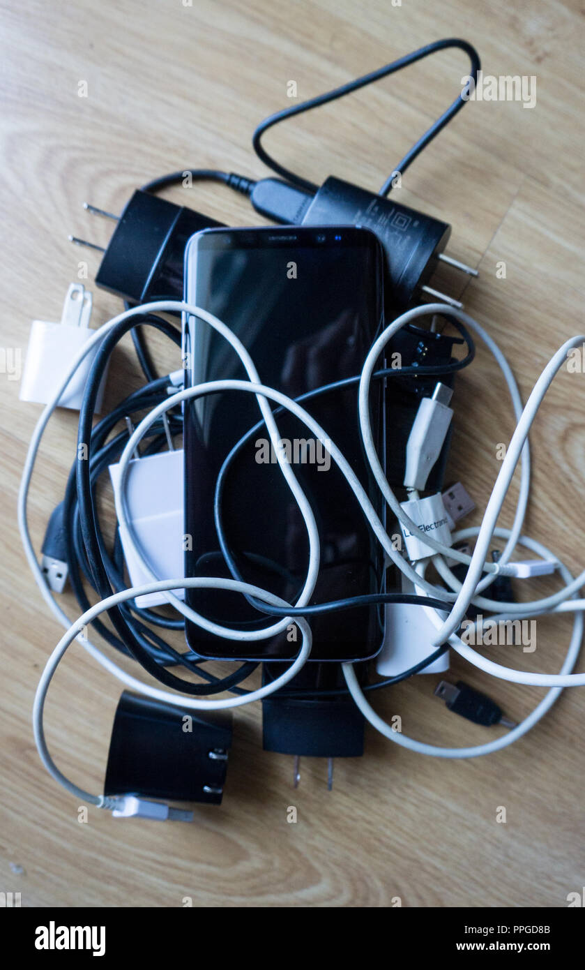 Smartphone tangled in differnt cables chargers usb and black and white ...