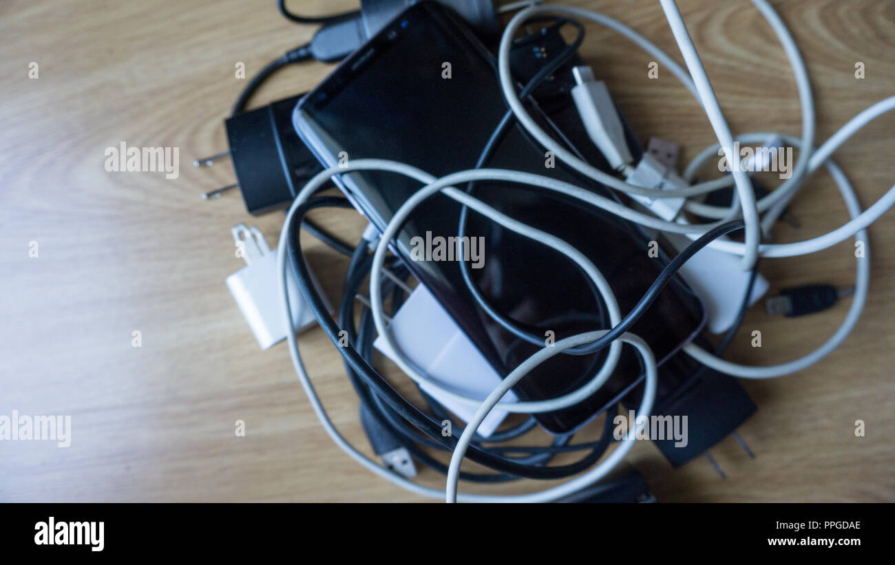 Smartphone tangled in differnt cables chargers usb and black and white ...