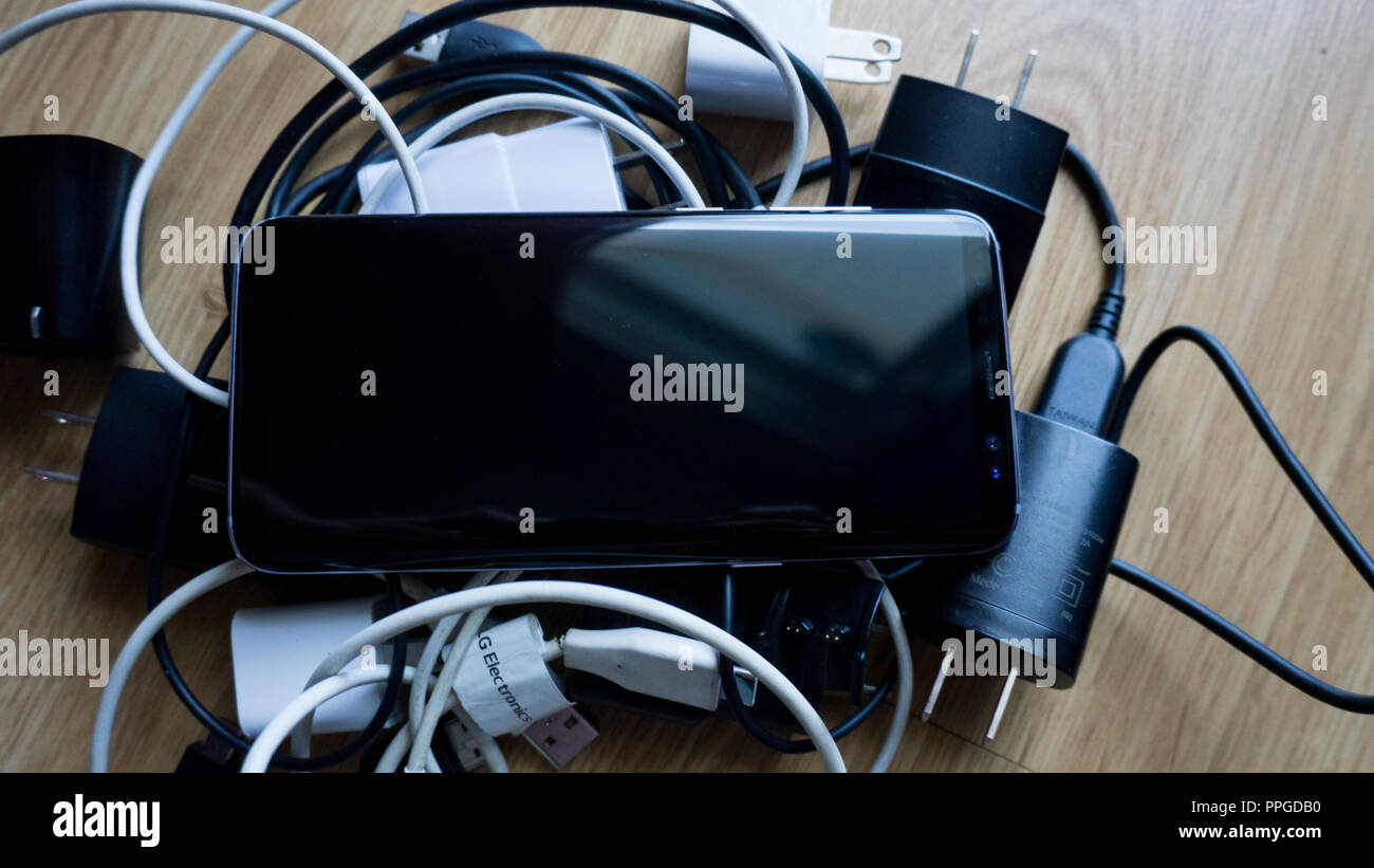 Smartphone tangled in differnt cables chargers usb and black and white ...