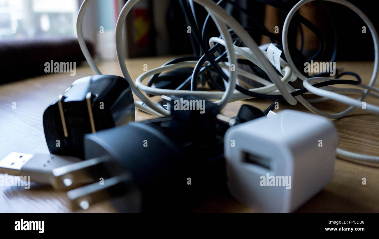 Smartphone tangled in differnt cables chargers usb and black and white ...