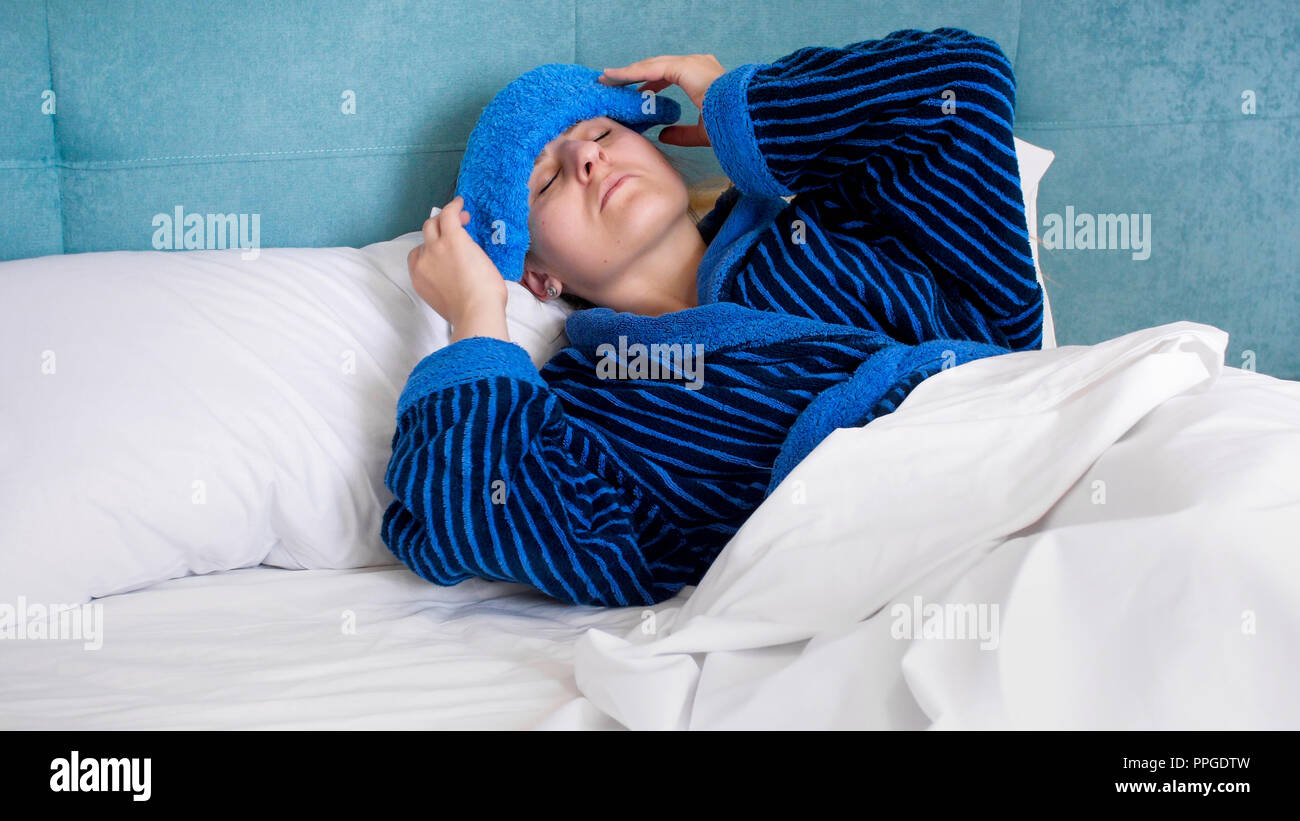 Photo of sick woman suffering from head ache putting wet compress on ...