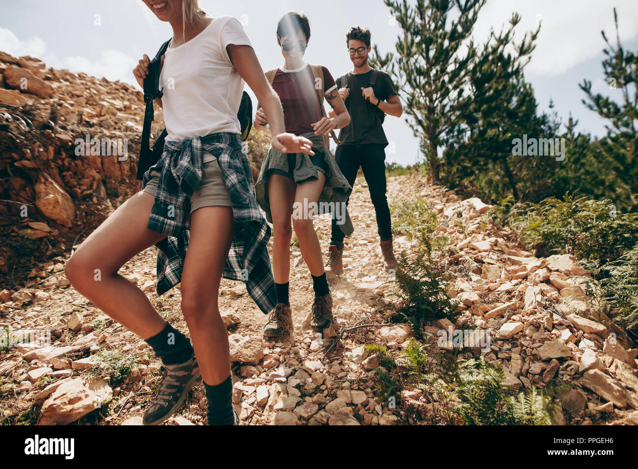 Explorer friends walking down a rocky path in a forest. Group of ...